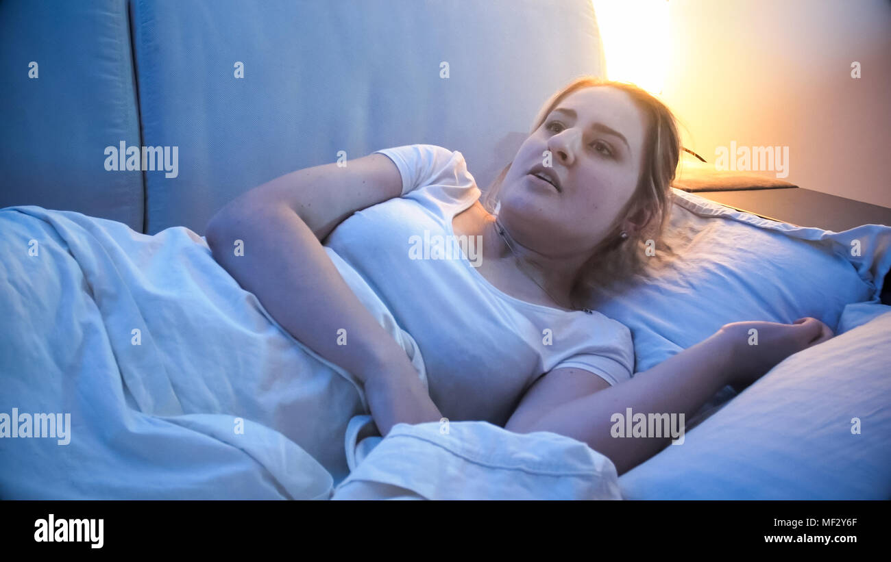 Portrait of scared young woman waking up at night because of nightmare ...