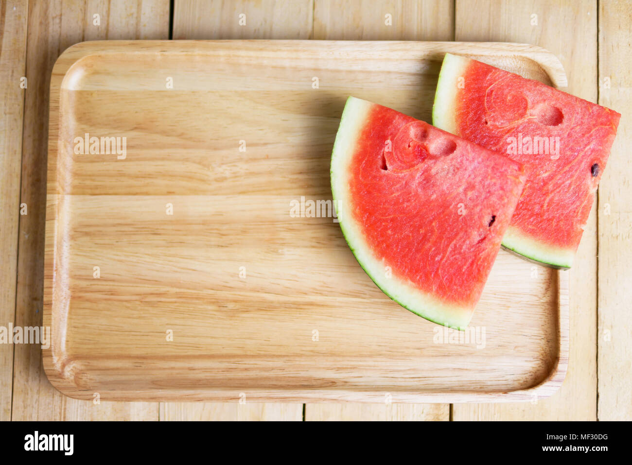 Red watermelon is cut into 2 pieces on a wooden board. On the wood ...