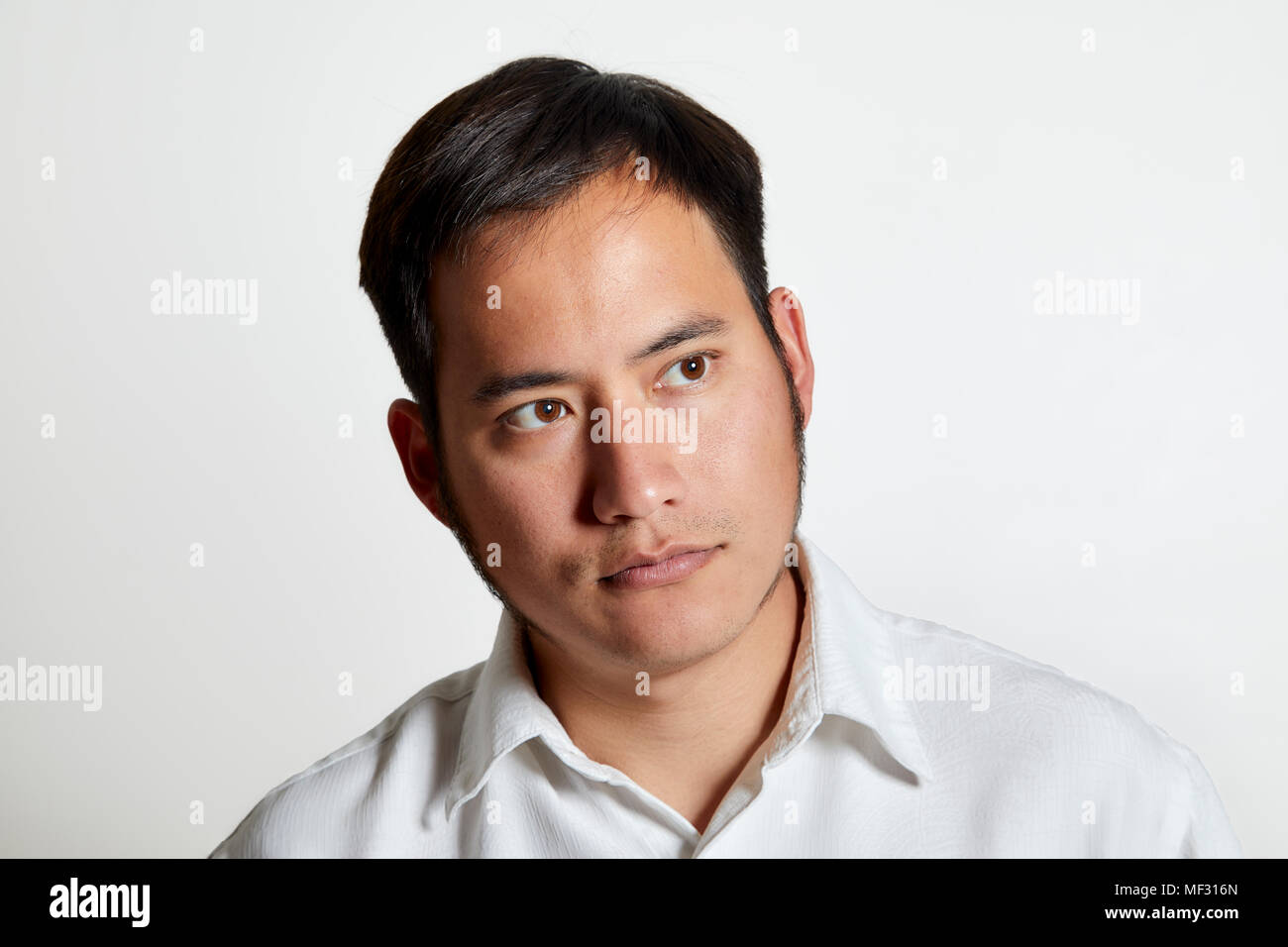Young Adult man with a serious expression, wearing a white shirt ...