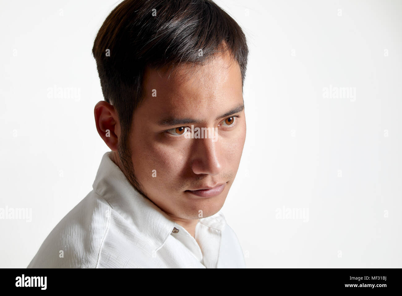 Young Adult man with a serious expression, wearing a white shirt ...
