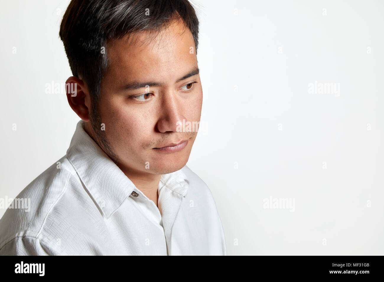 Young Adult man with a serious expression, wearing a white shirt ...