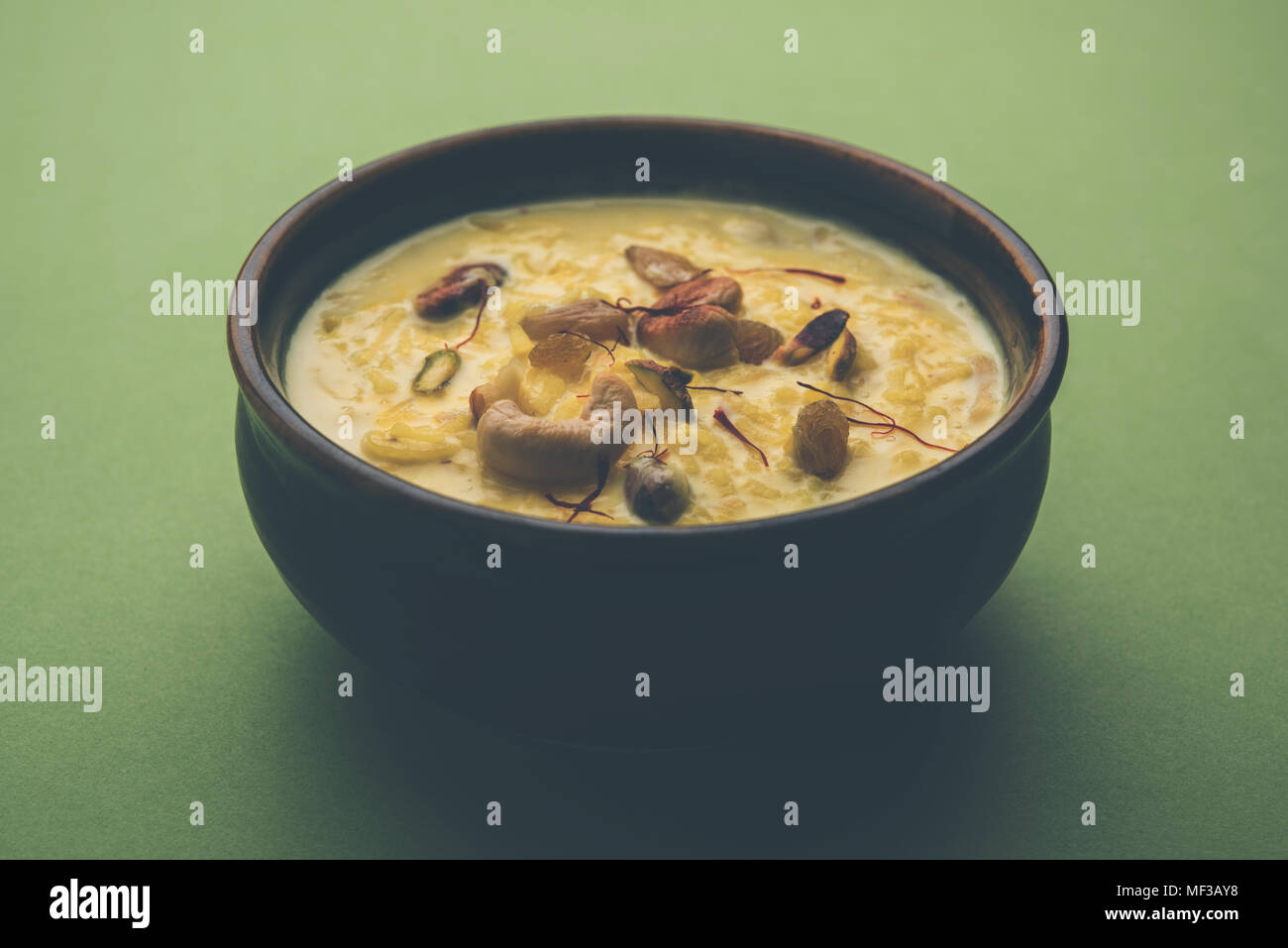 kheer or rice pudding is an Indian dessert in a brown terracotta bowl ...