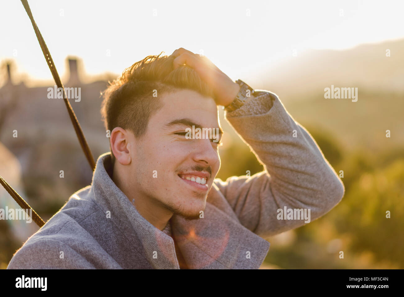 Portrait of smiling young man with hand in his hair at sunset Stock ...