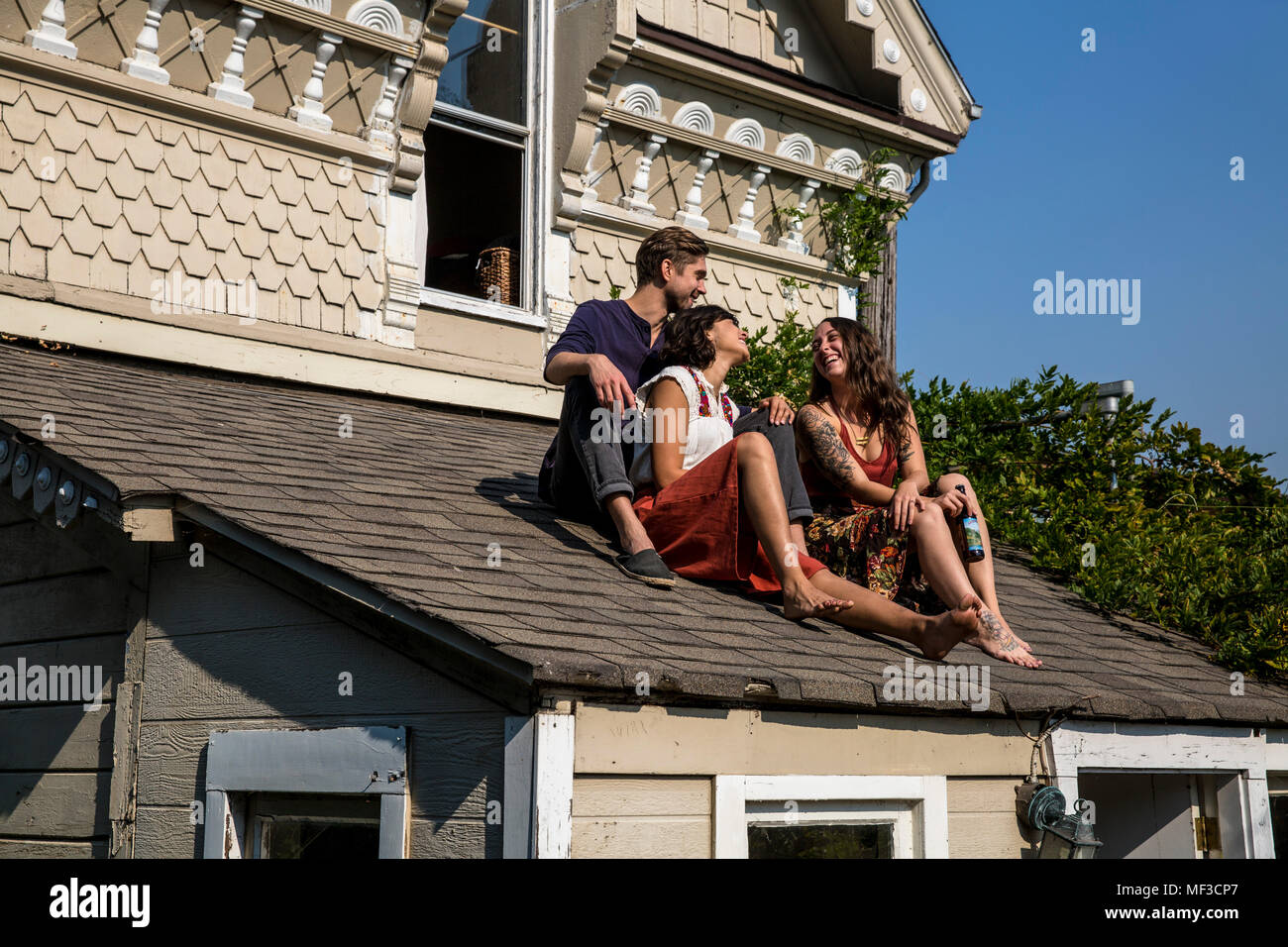 Happy friends sitting on roof Stock Photo - Alamy