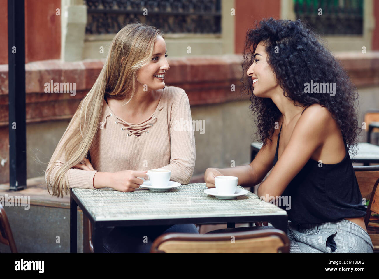 Two friends drinking coffee in sidewalk cafe Stock Photo - Alamy