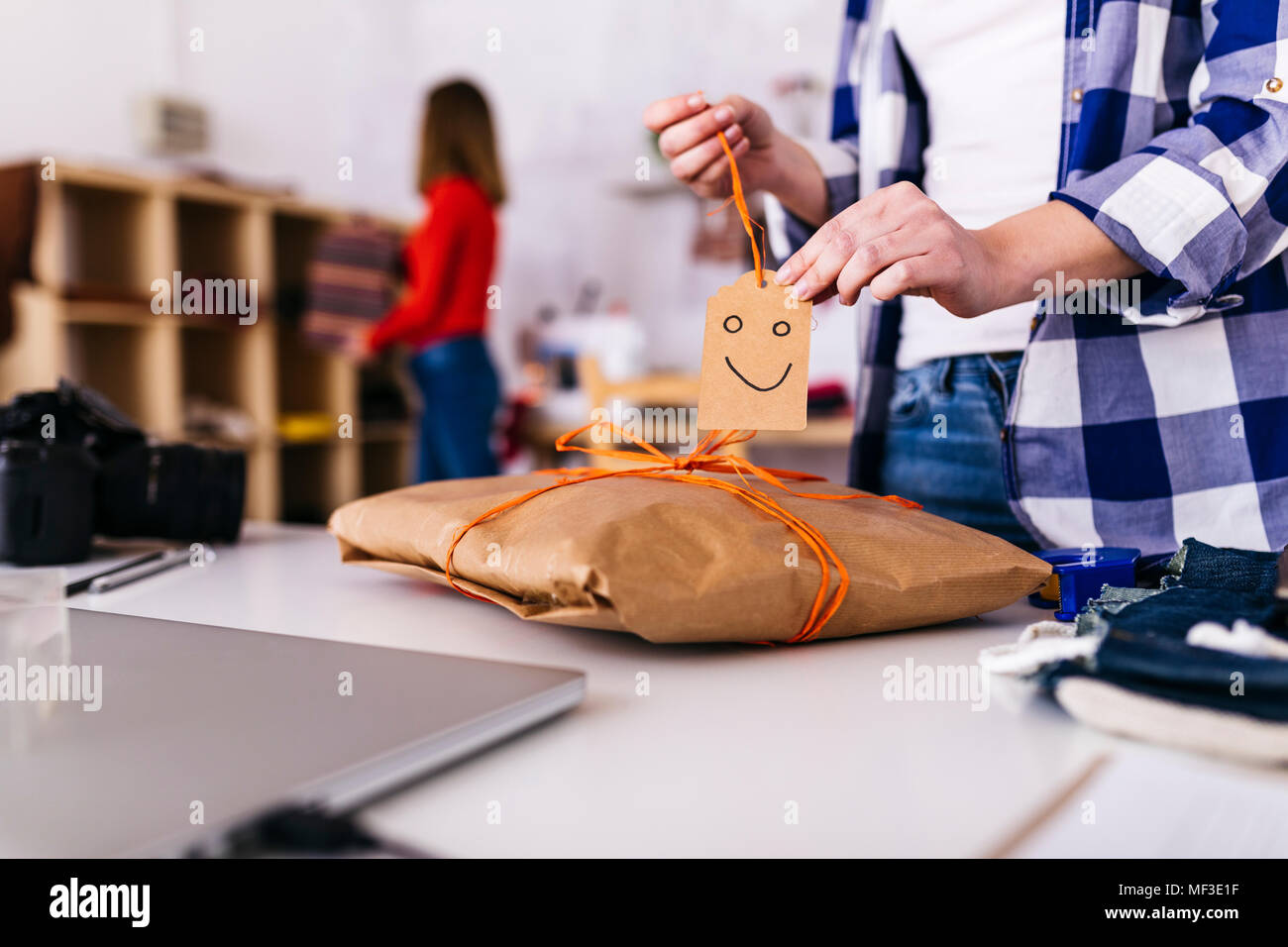 Close-up of fashion designer wrapping a package in studio with smiley ...