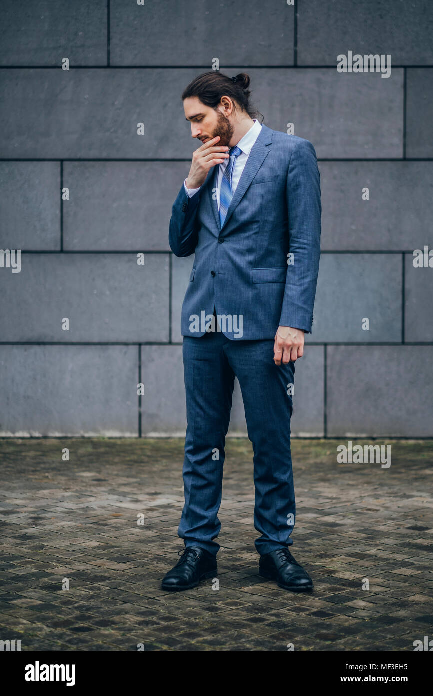 Serious businessman standing outdoors looking down Stock Photo - Alamy