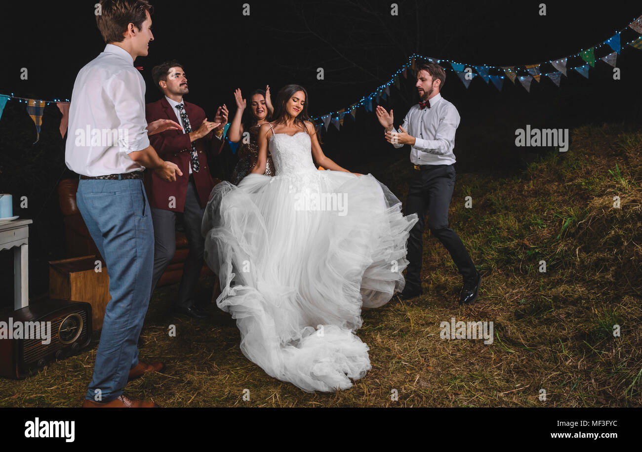 Happy bride dancing and having fun while her friends clapping on a ...