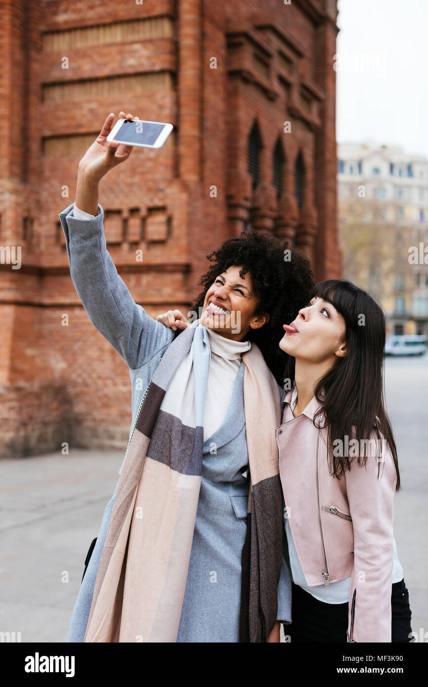 Spain, Barcelona, two playful women taking a selfie at a gate Stock ...