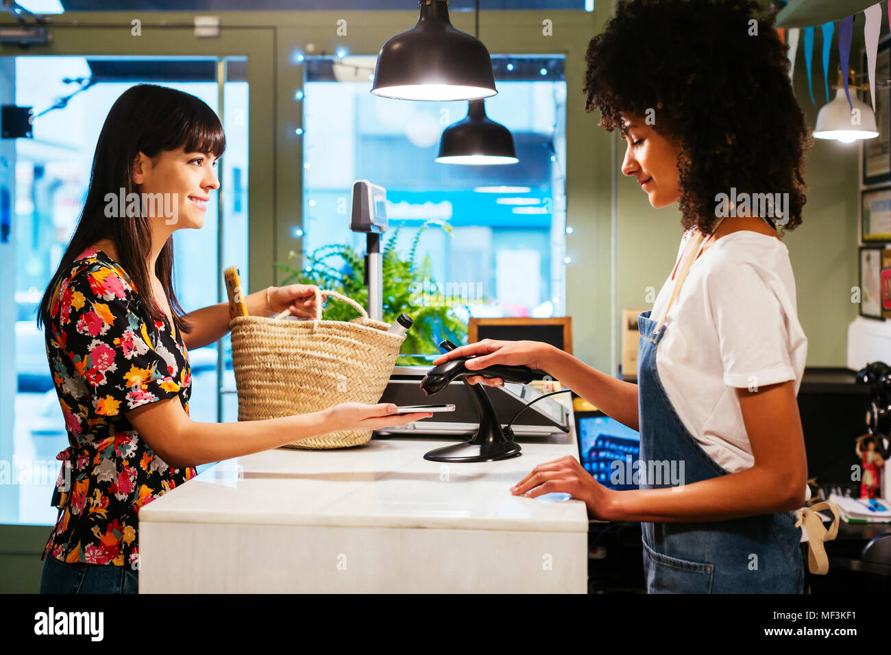 Customer paying cashless with smartphone at counter of a store Stock ...