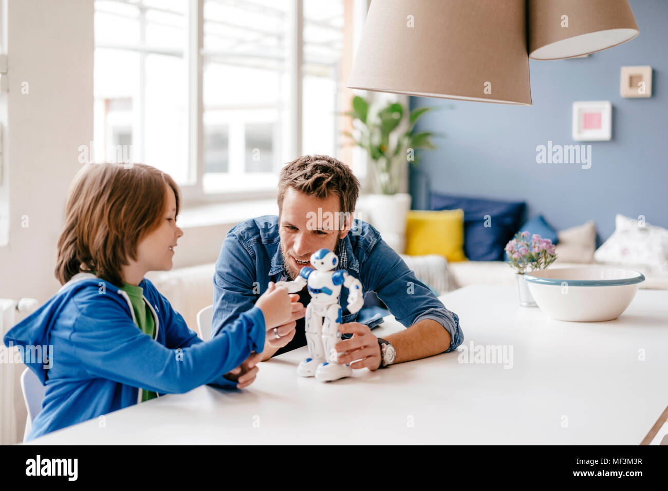 Happy father and son playing with robot on table at home Stock Photo ...