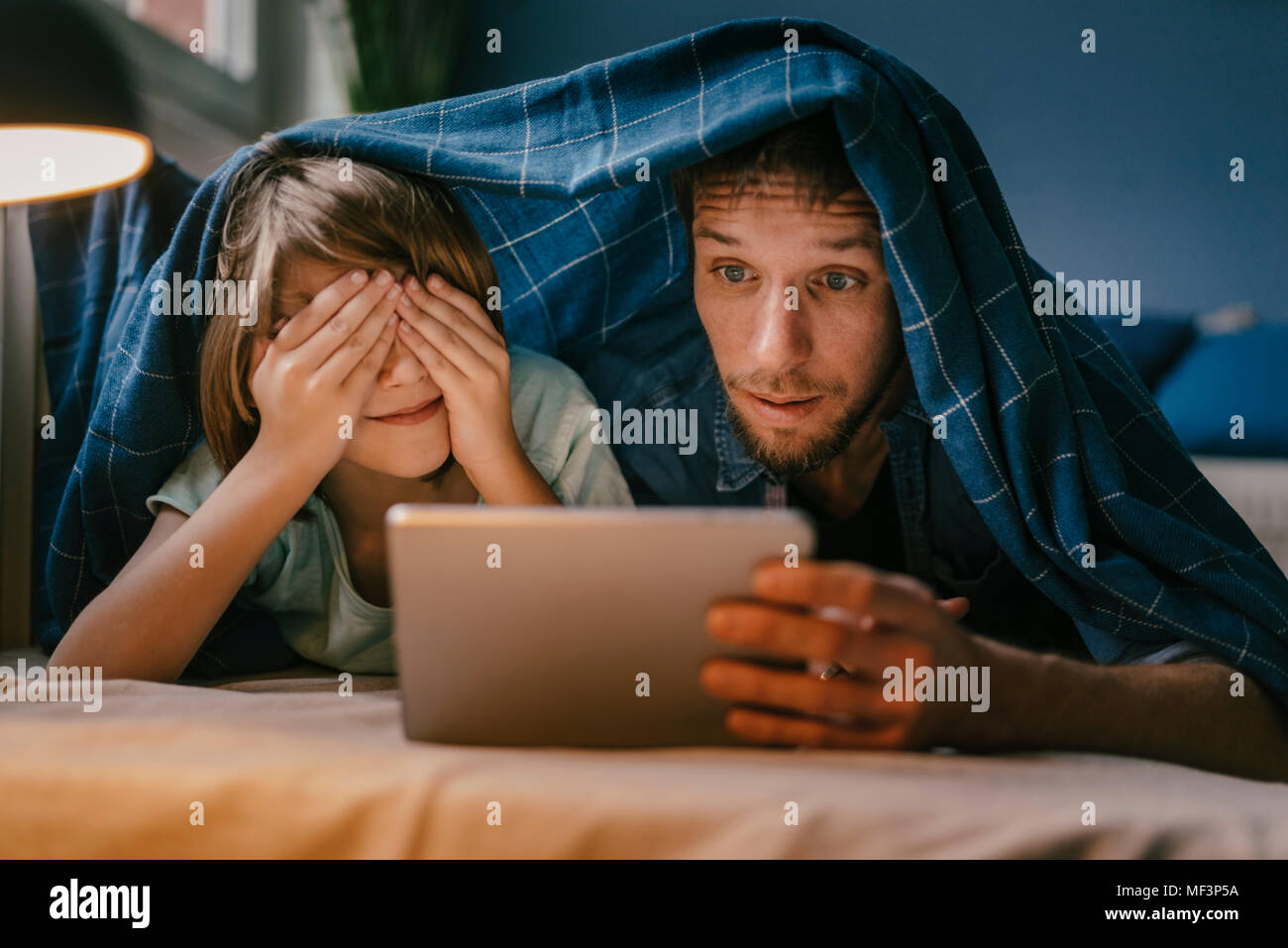Excited father son watching movie tablet under blanket hi-res stock ...