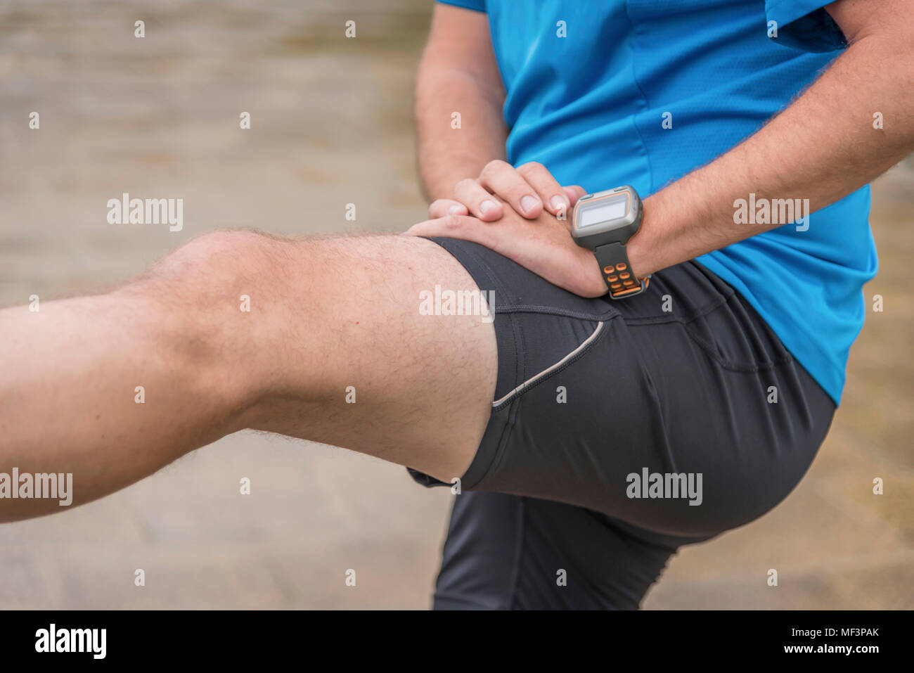 Man stretching leg, wearing a smartwatch Stock Photo - Alamy