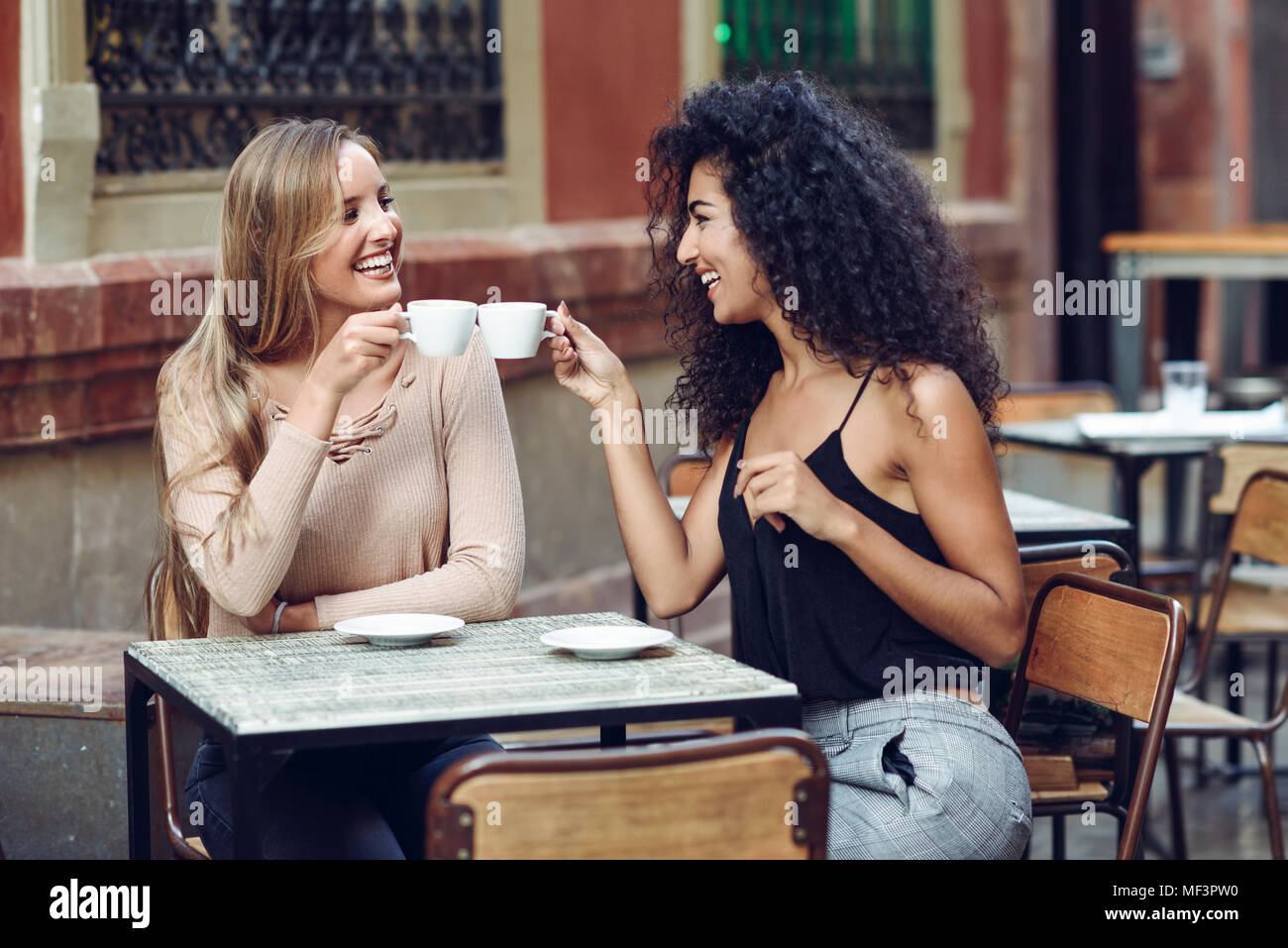 Two happy friends drinking coffee in sidewalk cafe Stock Photo - Alamy