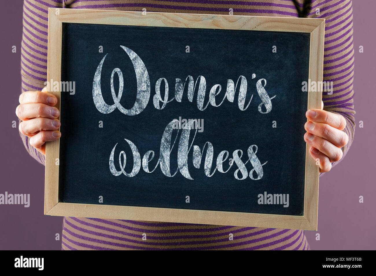 Female hands holding small black chalkboard in front of the body with ...