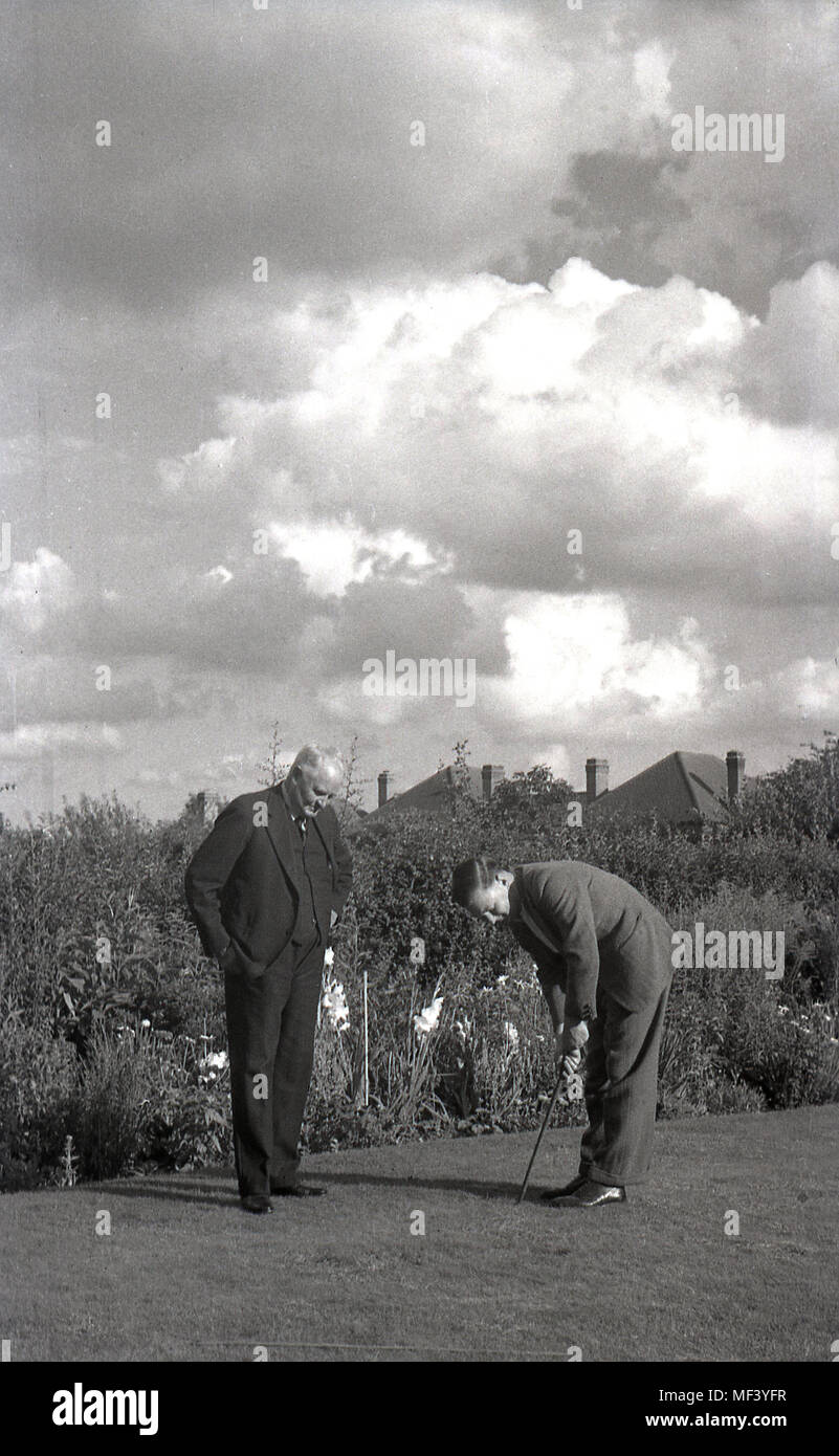 1950, historical, golf in the garden, two men wearing suit & ties, a ...