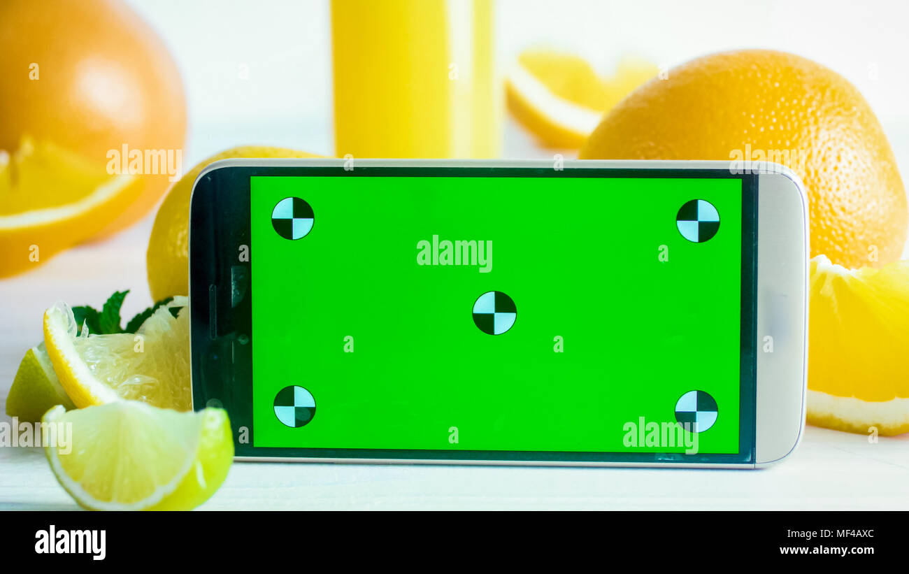 Closeup image of smrtphone with empty green screen on table next to ...