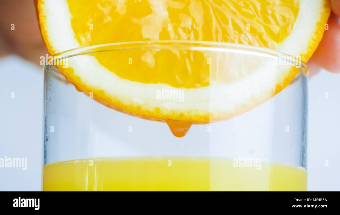 Macro image of hand squeezing orange juice in glass Stock Photo - Alamy