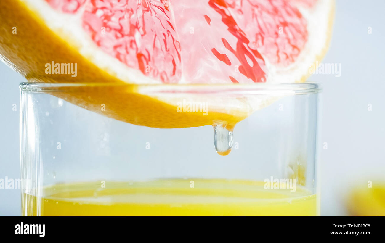 Macro image of juice droplet dripping from grapefruit slice in glass ...
