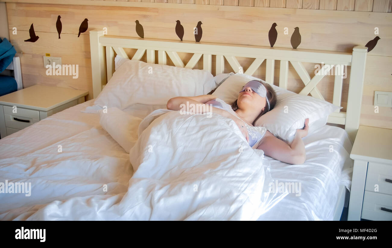 Beautiful young woman in sleeping blindfold mask in bed at hotel Stock ...