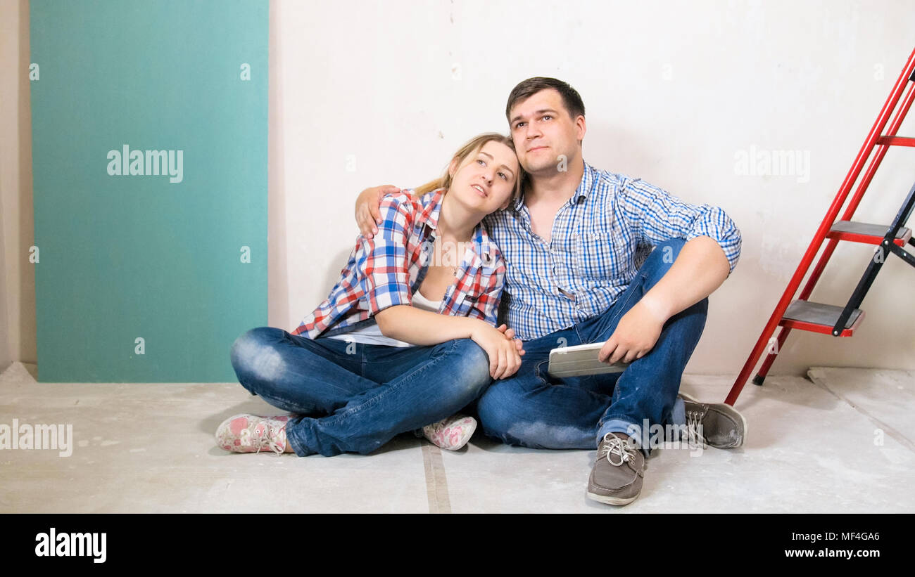 Beautiful loving couple hugging on floor of their new house under ...