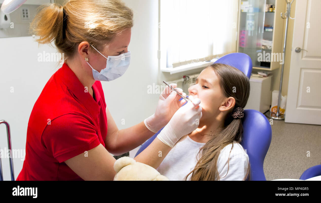 Female pediatric dentist inspecting girls teeth with instruments Stock ...