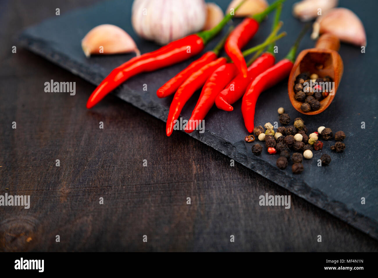 Red chili pepper, garlic and hot peppercorns on a dark background ...