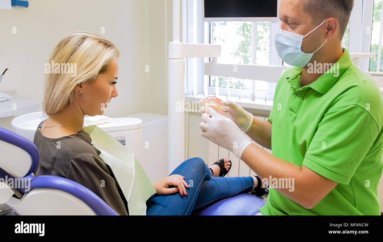 Portrait of beautiful blonde woman talking with dentist about mnethods ...