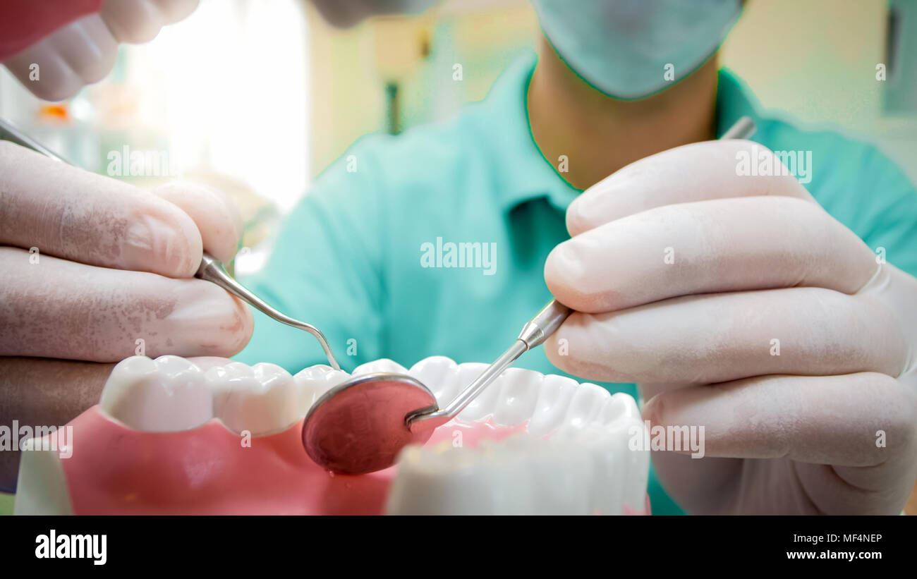 Closeup image of male dentist inspecting teeth with mirror and special ...