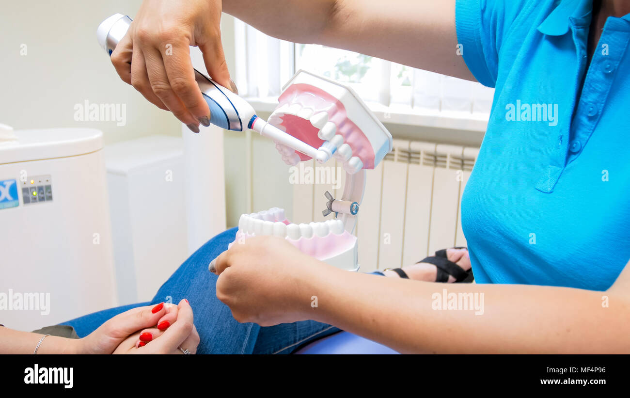 Closeup image of dentist educating patient about cleaning teeth with ...