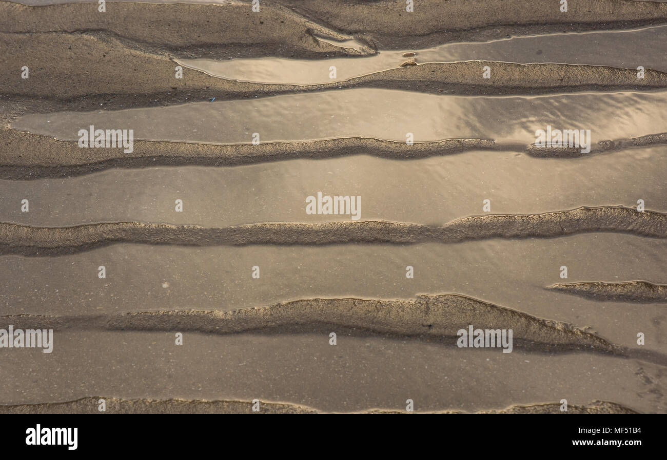 Close up shot of a sandy beach with wave patterns left by water ...