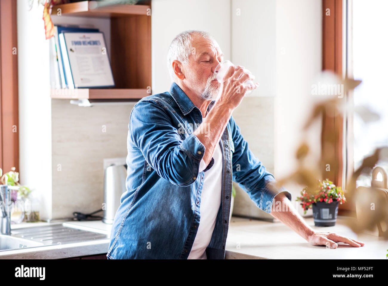 Senior man drinking water in the kitchen Stock Photo - Alamy