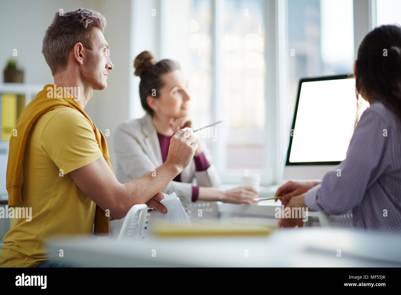 Businessman showing computer screen to coworkers in creative office ...