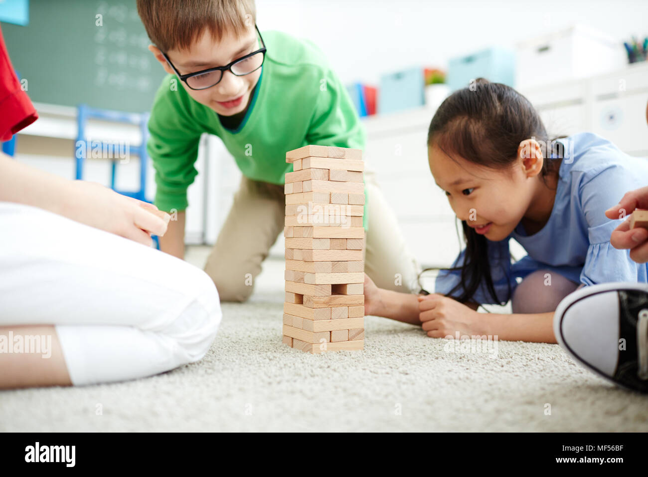 Elementary school kids sitting on the floor and playing with wooden ...
