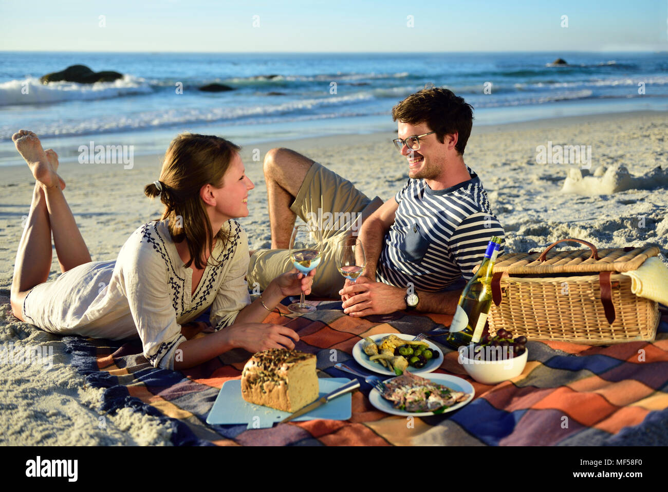 Happy couple having a picnic on the beach Stock Photo - Alamy