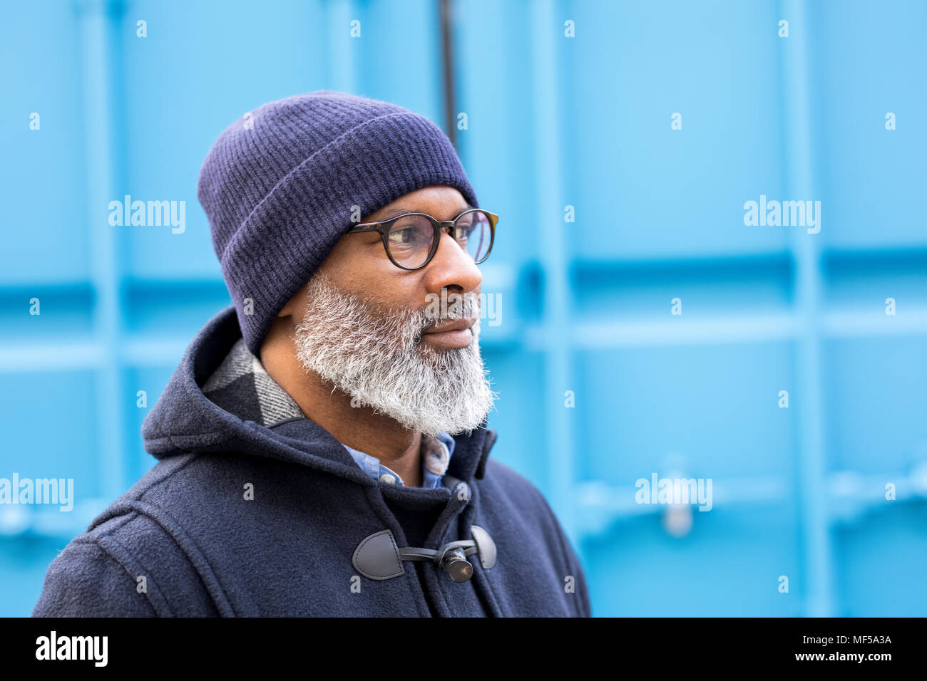 Portrait of man wearing blue woolly hat watching something Stock Photo ...