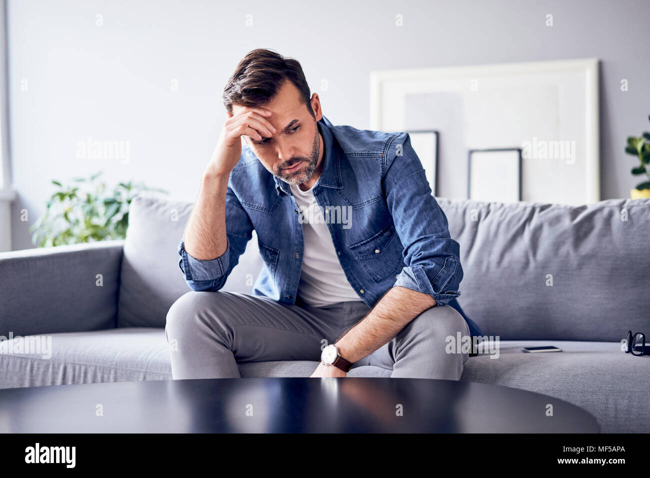 Sad man sitting on couch hi-res stock photography and images - Alamy