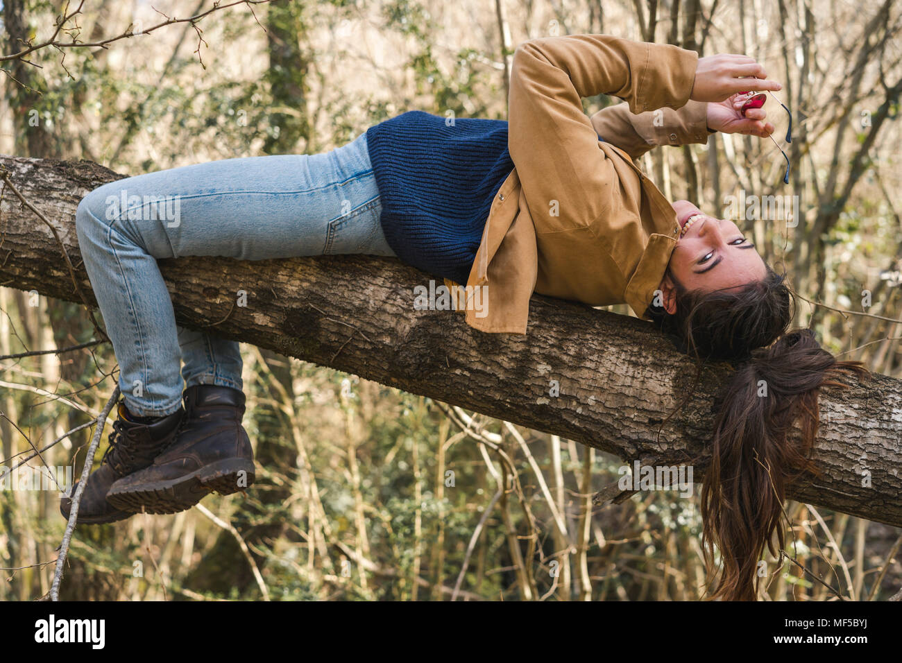 Happy young woman lying on a tree trunk in nature Stock Photo - Alamy