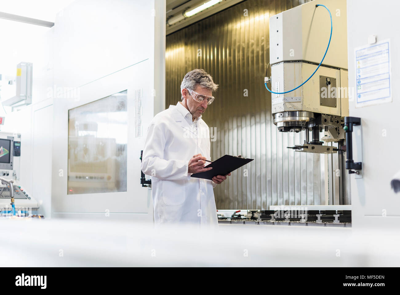Controller with clipboard checking a machine Stock Photo - Alamy
