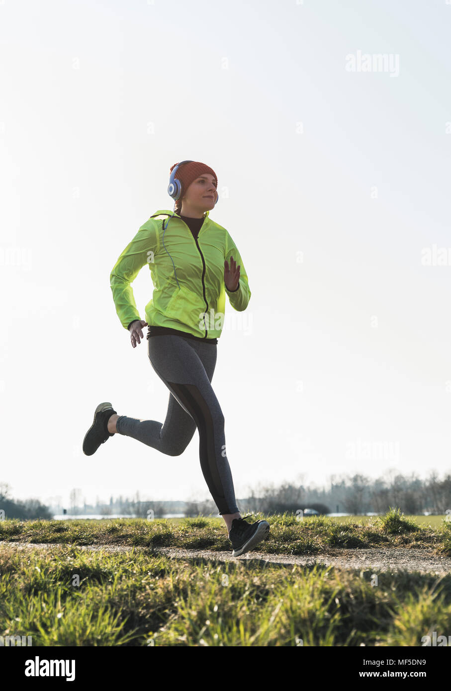 Young woman with headphones running on rural path Stock Photo - Alamy