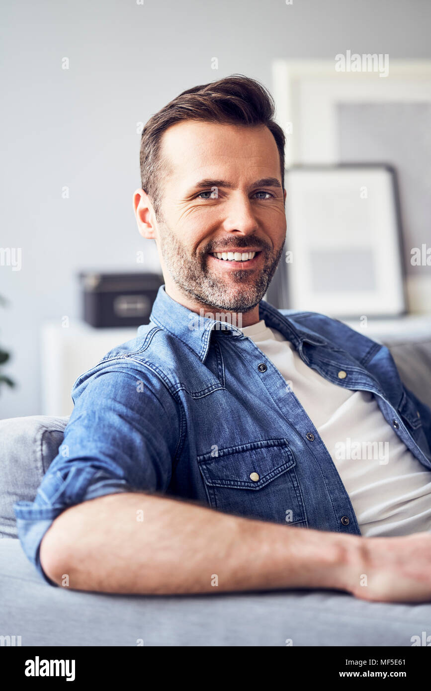 Portrait of smiling man sitting on sofa Stock Photo - Alamy