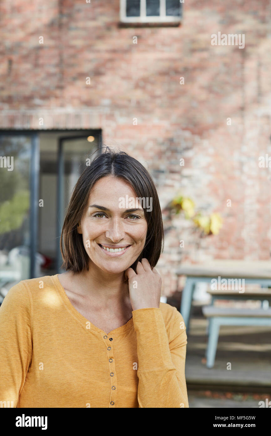 Portrait of smiling woman in front of her home Stock Photo - Alamy