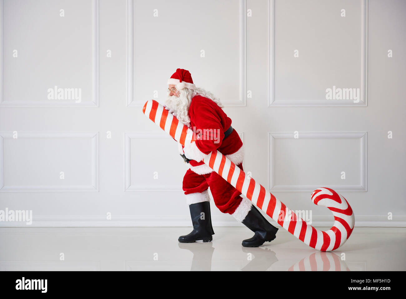 Santa Claus carrying oversized candy cane Stock Photo - Alamy