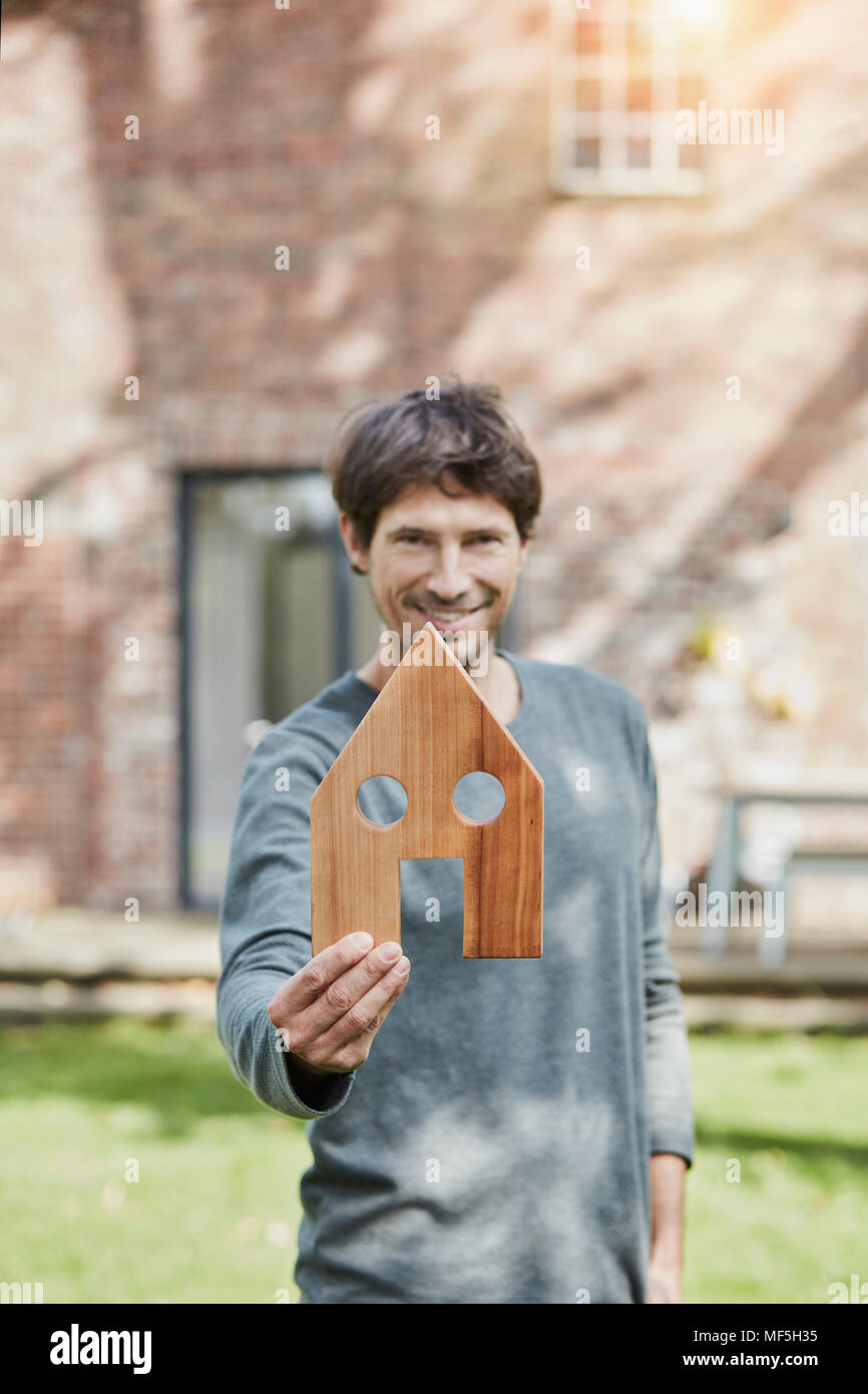 Portrait of smiling man in front of his home holding house model Stock ...