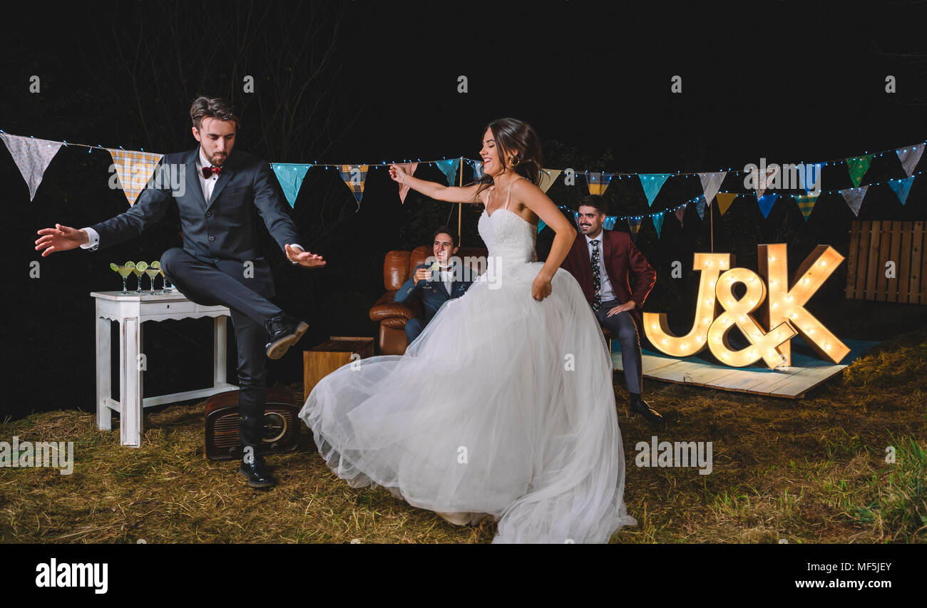 Happy bride and man dancing on a night field party Stock Photo - Alamy