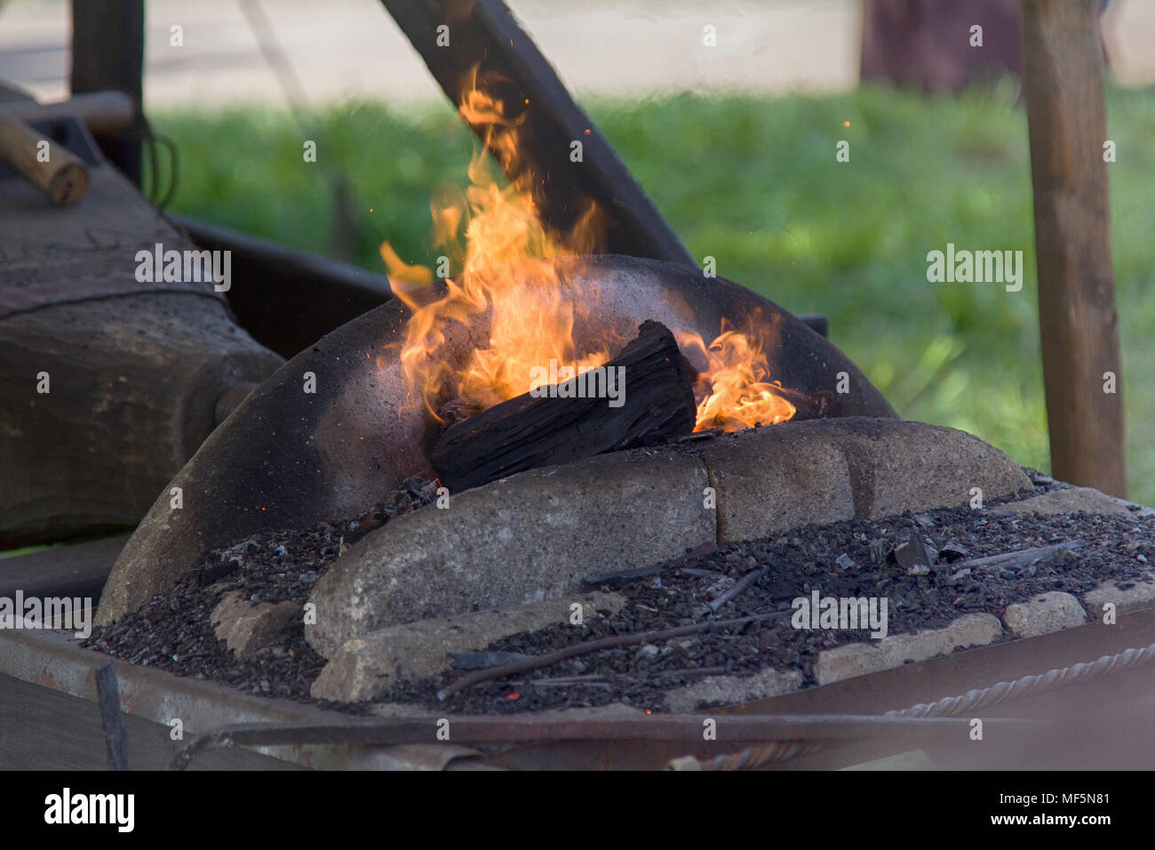Village Blacksmith near forge hearth and anvil at work. In background ...