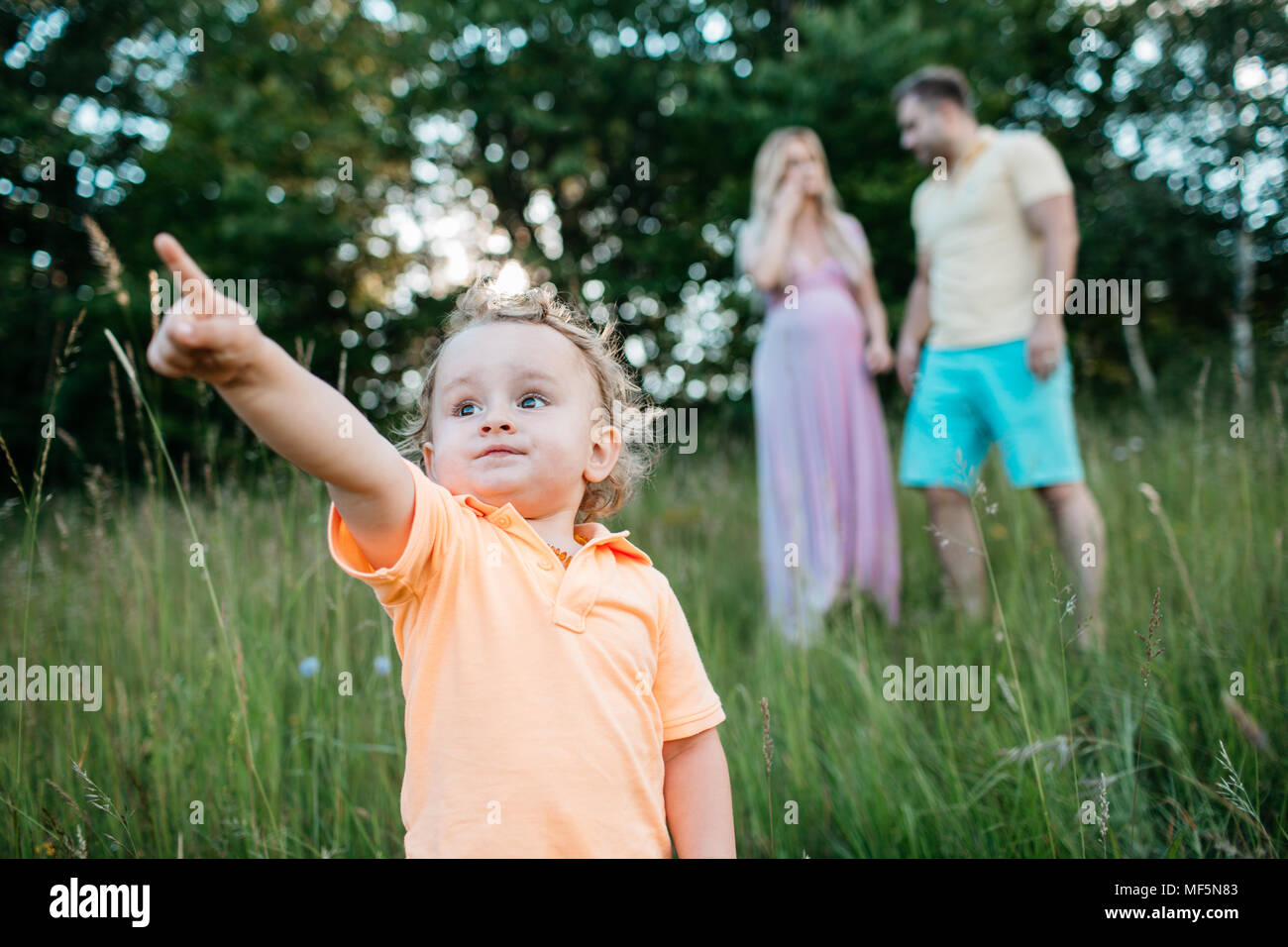 A portrait of a child pointing. A small boy standing on a field and ...