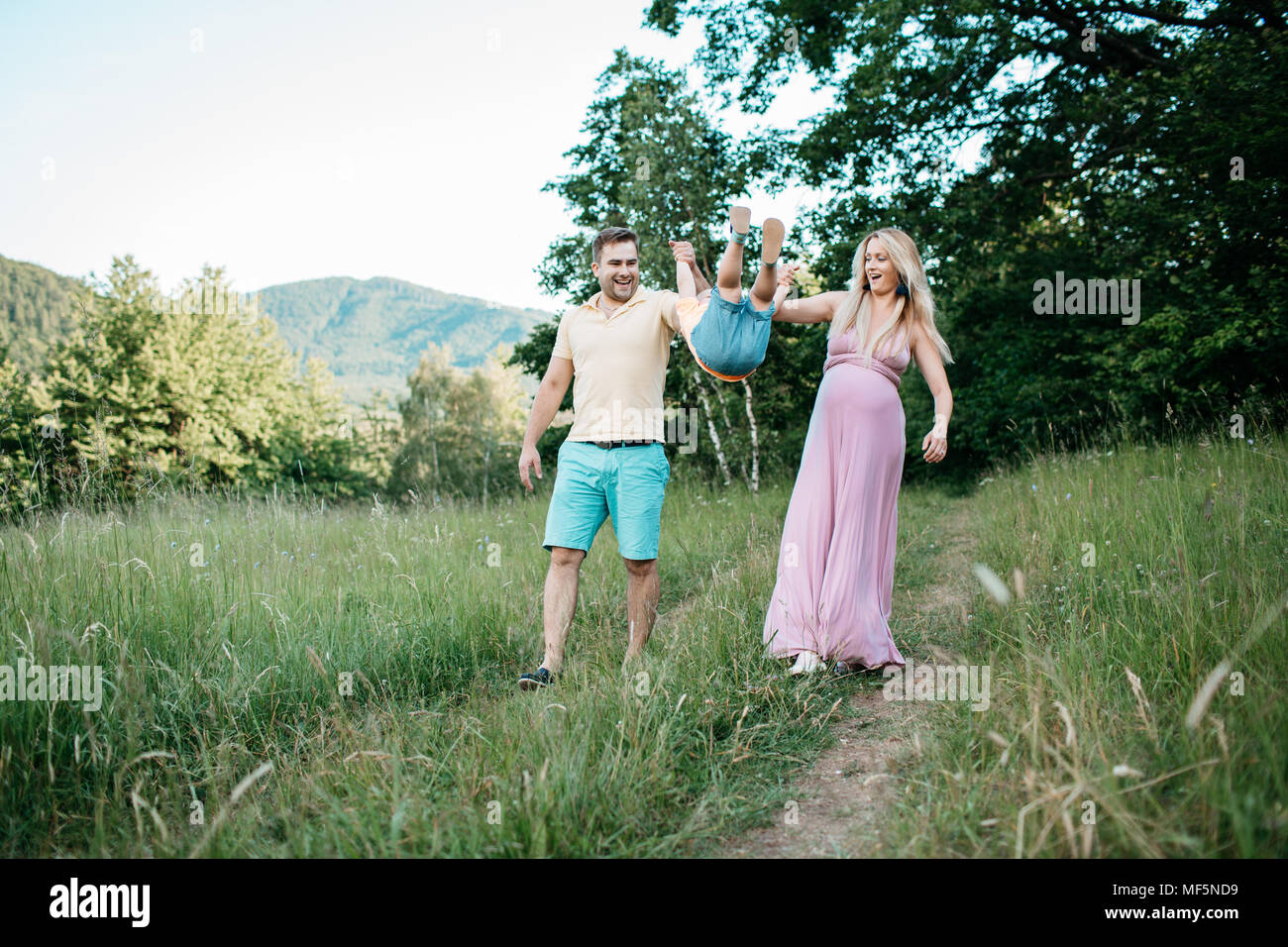 Happy parents lifting a child in the air. A father and a mother holding ...