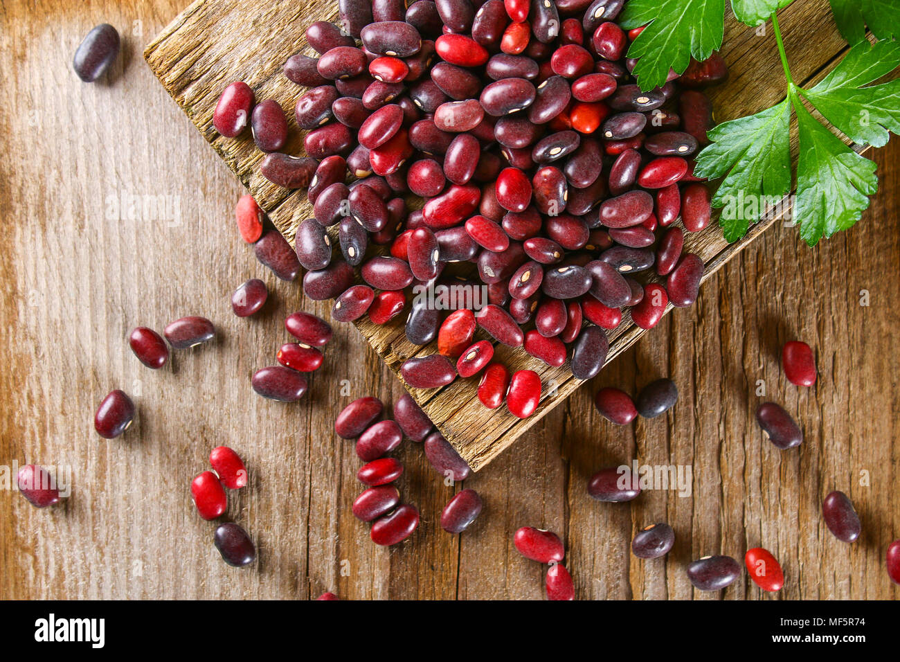 Red raw beans with greens on a wooden table Stock Photo - Alamy