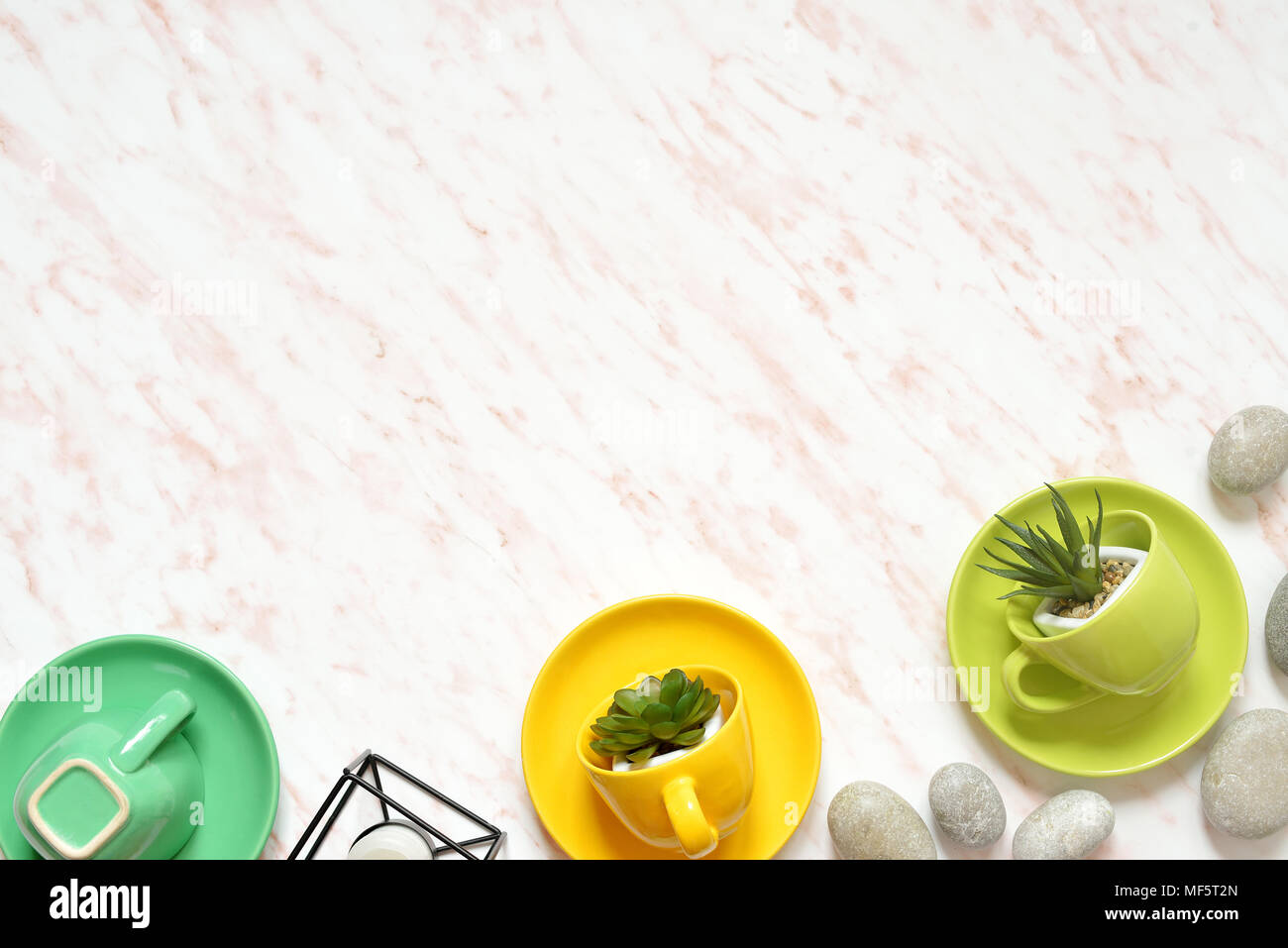 Flat lay of creative colored marble desk with green cup, stones and ...